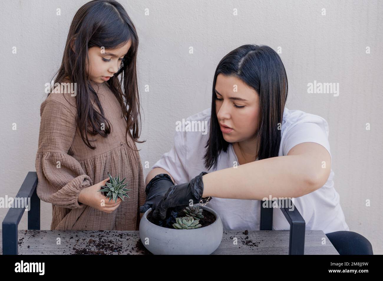 Mother and daughter planting in home garden. Beautiful mom and young ...