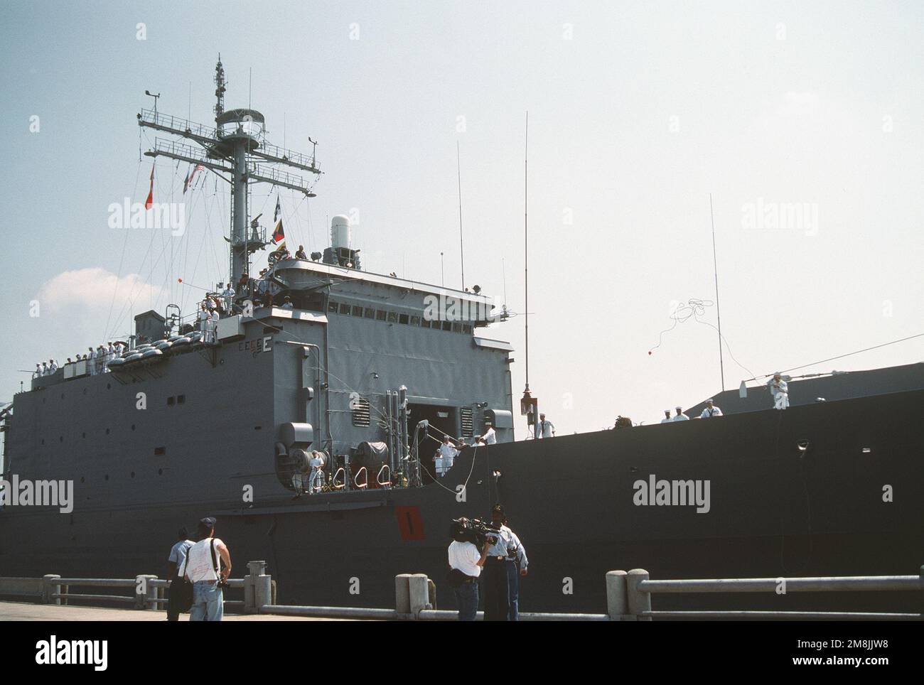 Heaving lines are tossed over to the pier from the tank landing ship ...