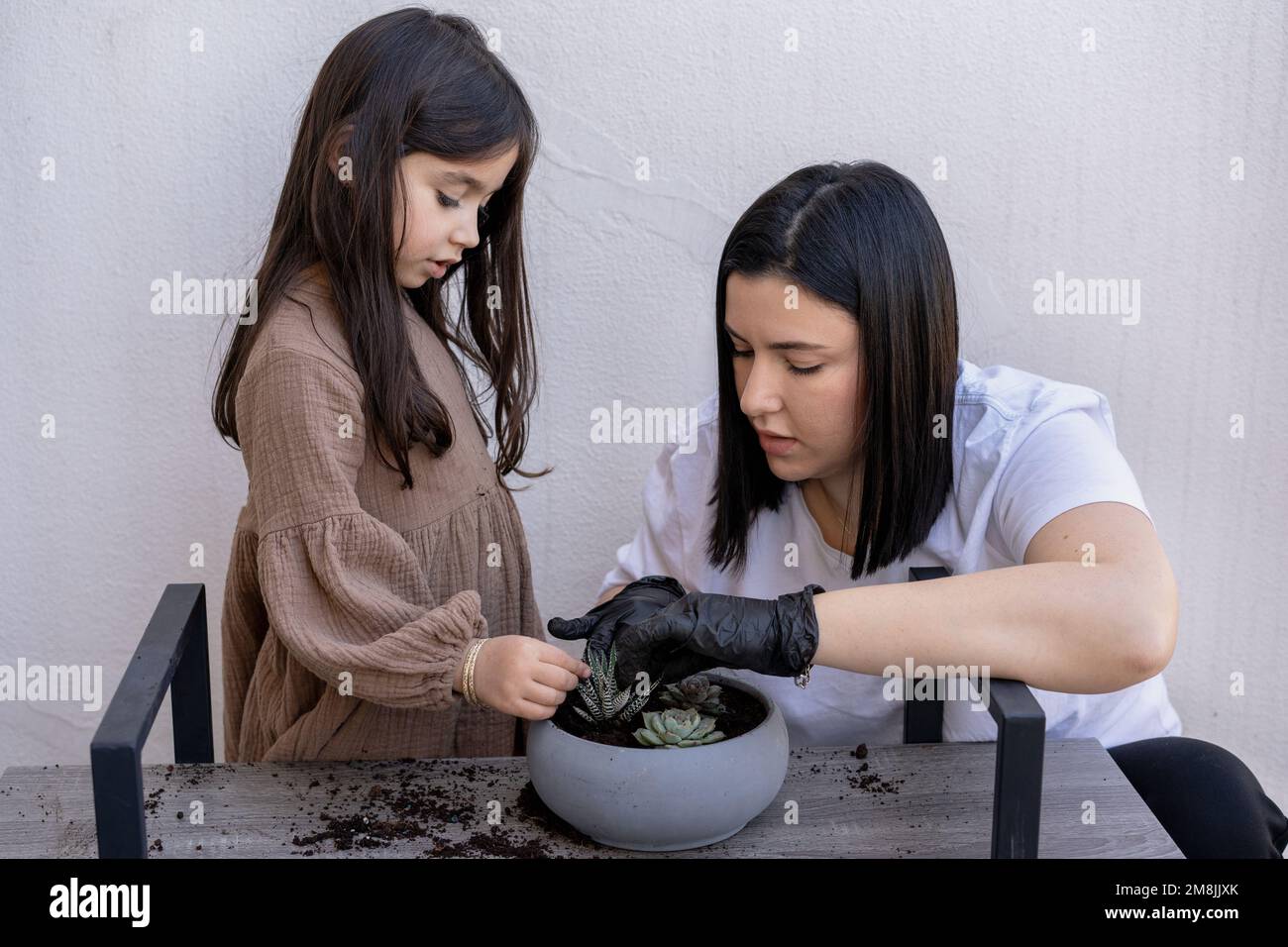 Mother and daughter planting in home garden. Beautiful mom and young ...