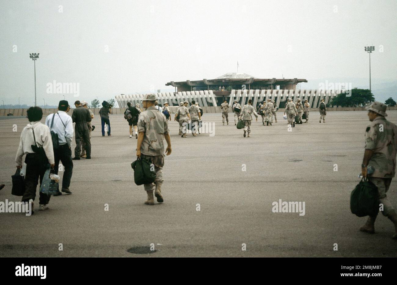 U.S. military personnel walk across the ramp toward the control tower ...