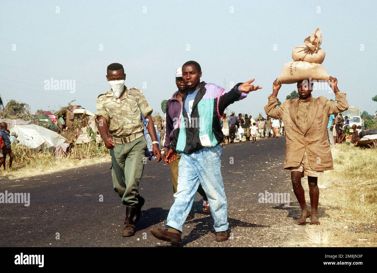 A stream of Rwandan refugees, carrying all their possession, walk into ...