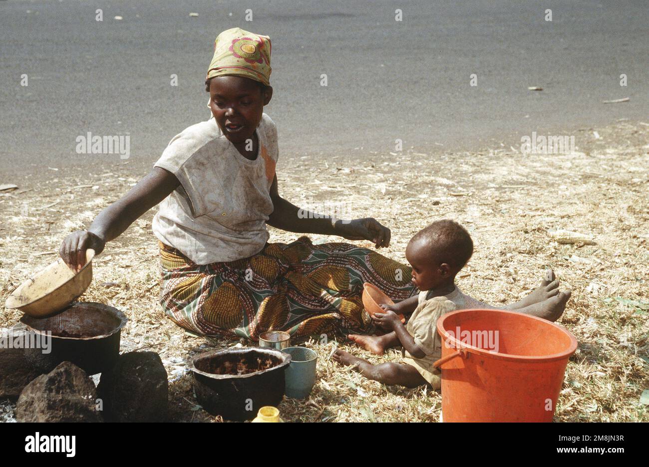 Rwandan refugees, mother and child eat beans from bowls, in the Kibumba ...