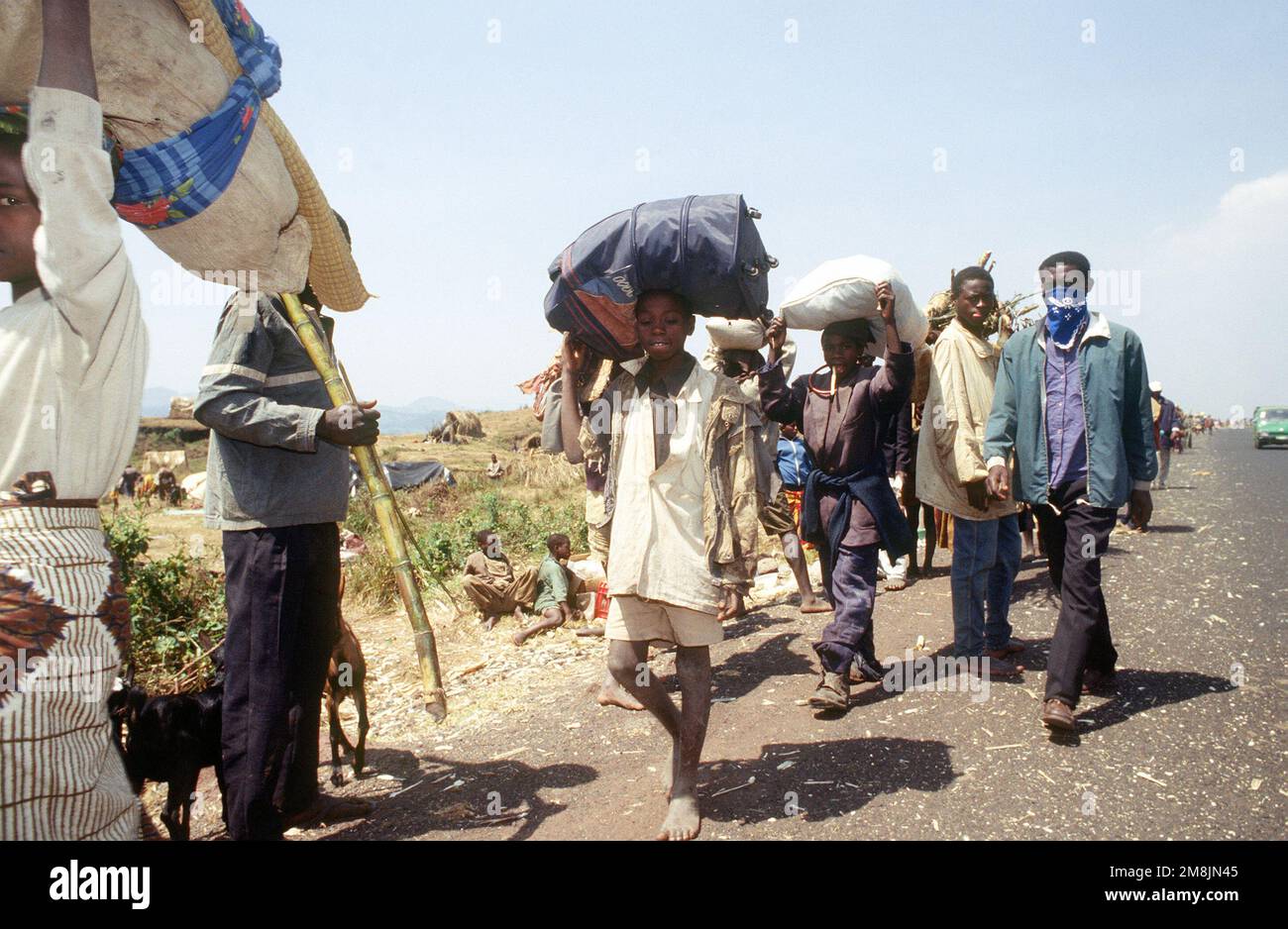 A stream of Rwandan refugees, carrying all their possession, walk into ...