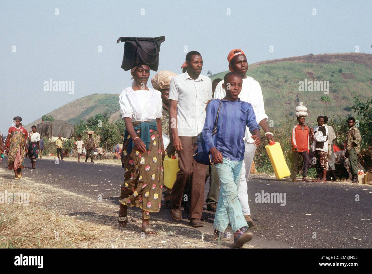 A stream of Rwandan refugees, carrying all their possession, walk into ...