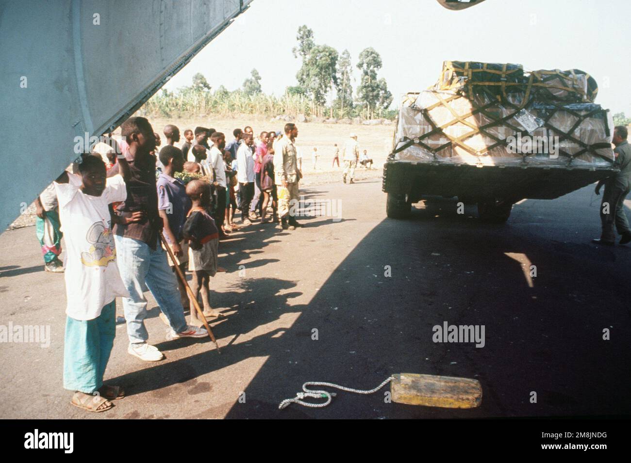 Rwandan refugees curiously observe cargo off-load operations of a C-141 ...