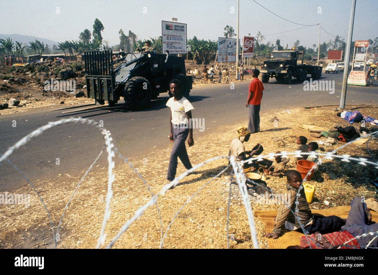 A US military forklift and truck pass by Rwandans who have come to Goma ...