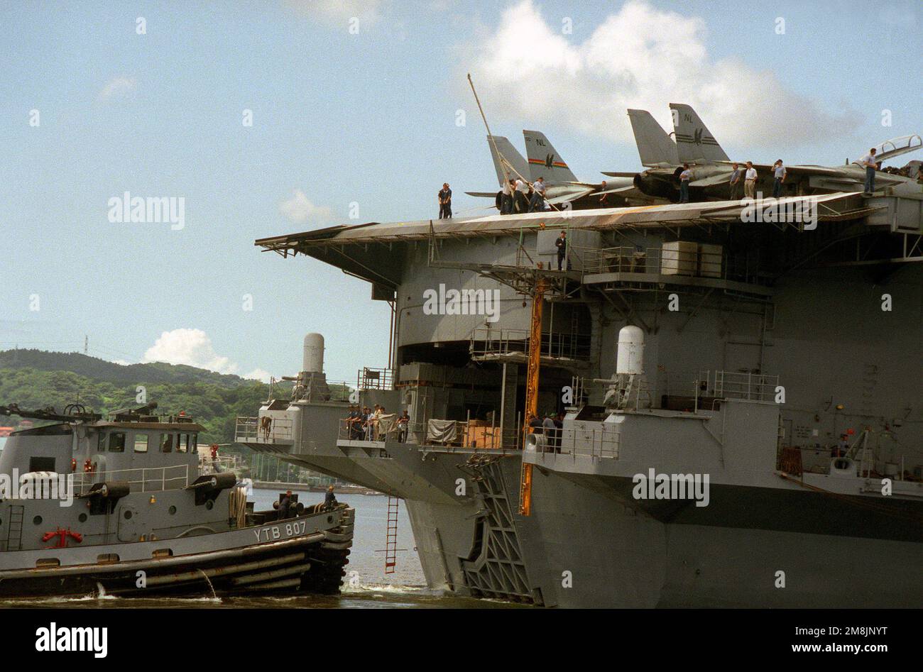 The large harbor tug MASSAPEQUA (YTB-807) moves up to the stern of the ...
