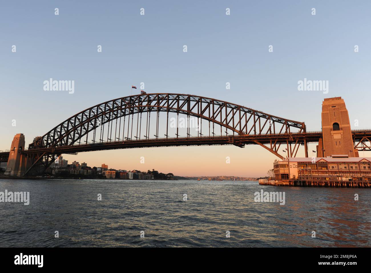 The iconic Sydney Harbour Bridge with Australia flags flying at sunset ...