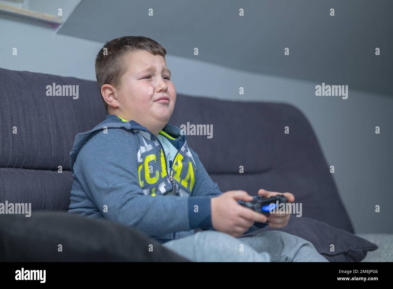 the boy is sitting on the couch, holding a joystick and playing a video ...