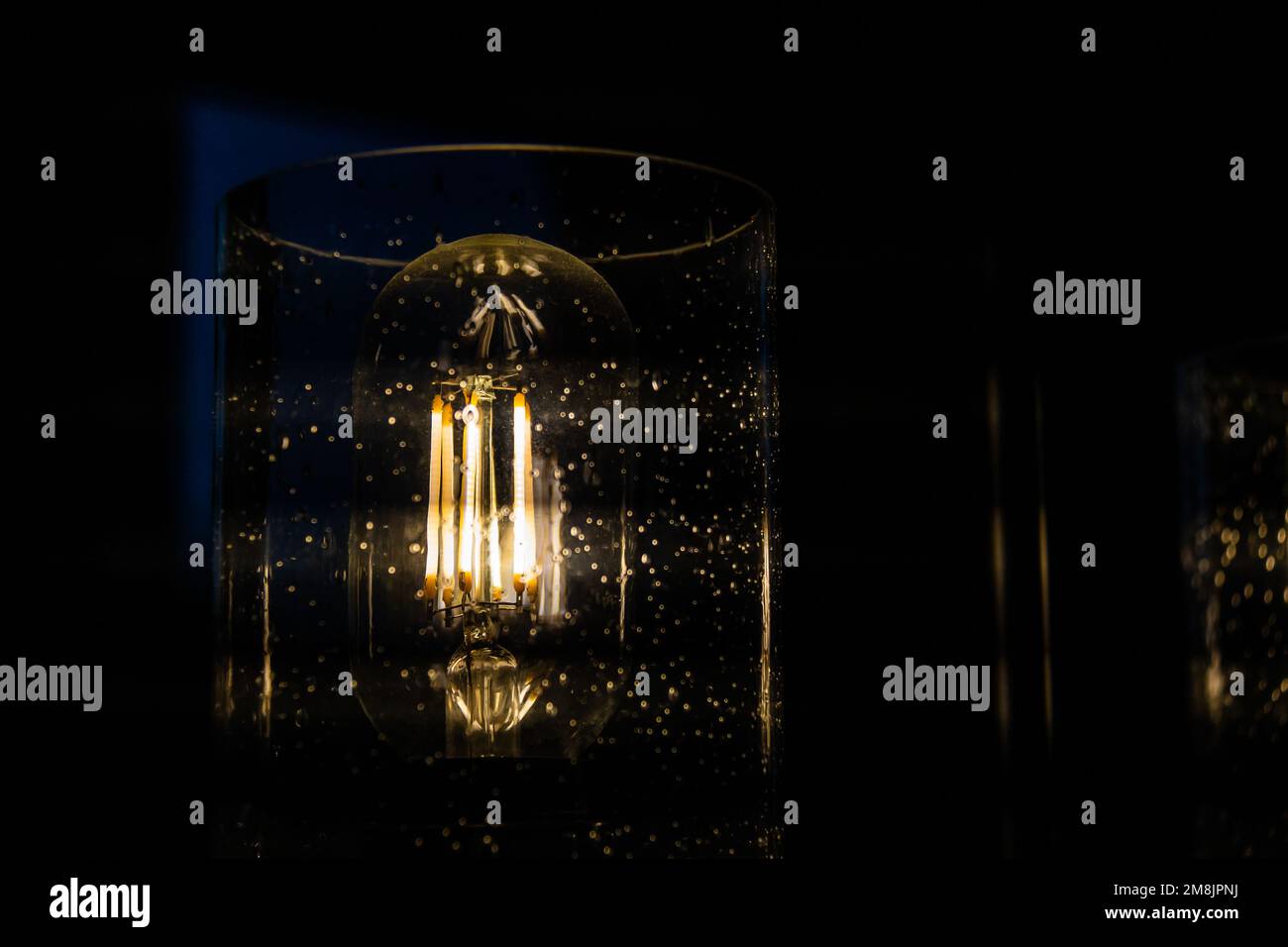 Retro style vintage light bulb in a glass enclosure with bubble texture ...