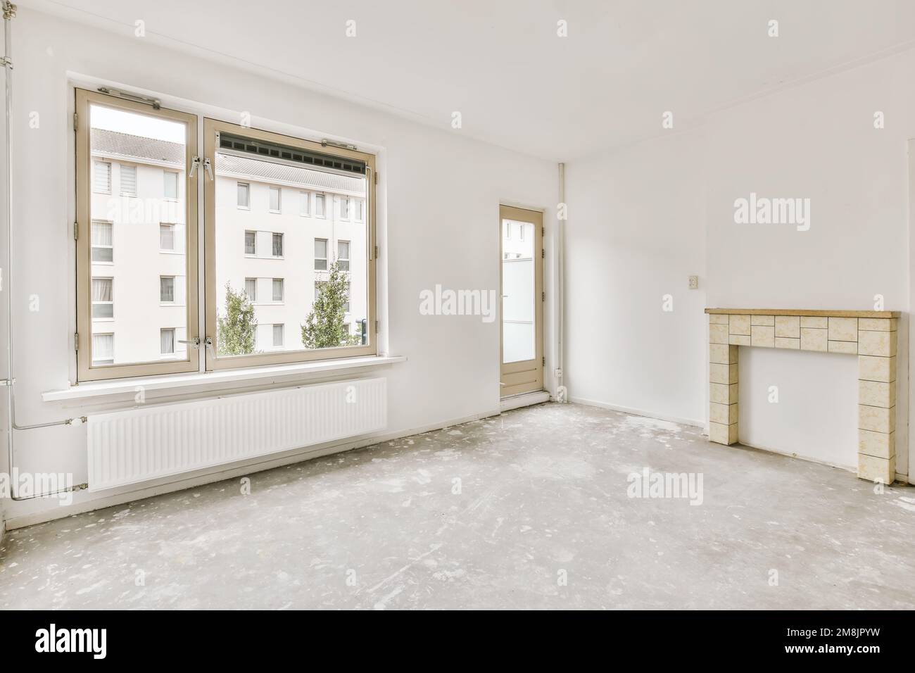 an empty room with a fire place in the middle part of the room is white ...