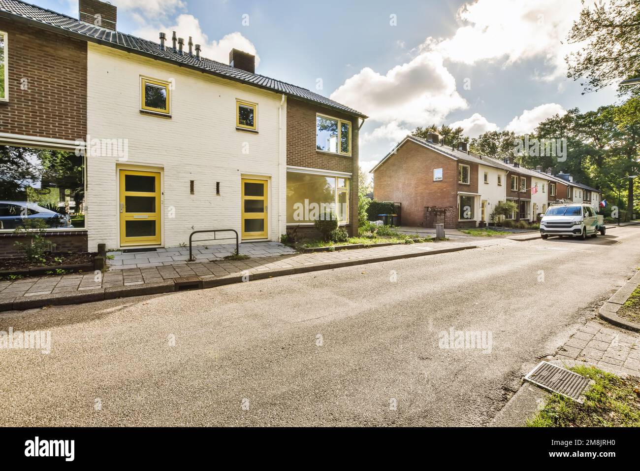 an empty street with houses in the background and clouds overhead over ...