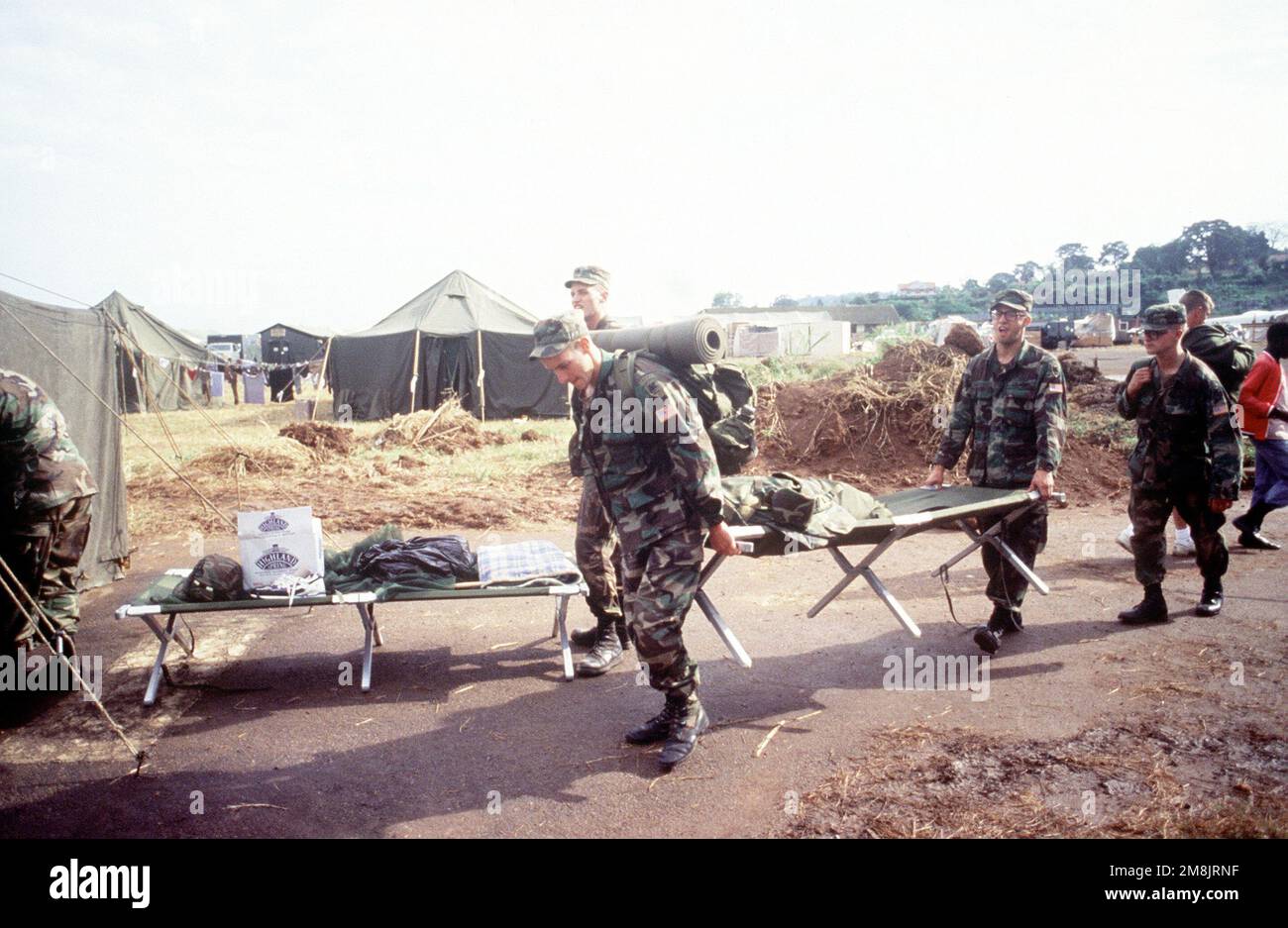 U.S. Army personnel move their belongings and cots from the hangar to ...