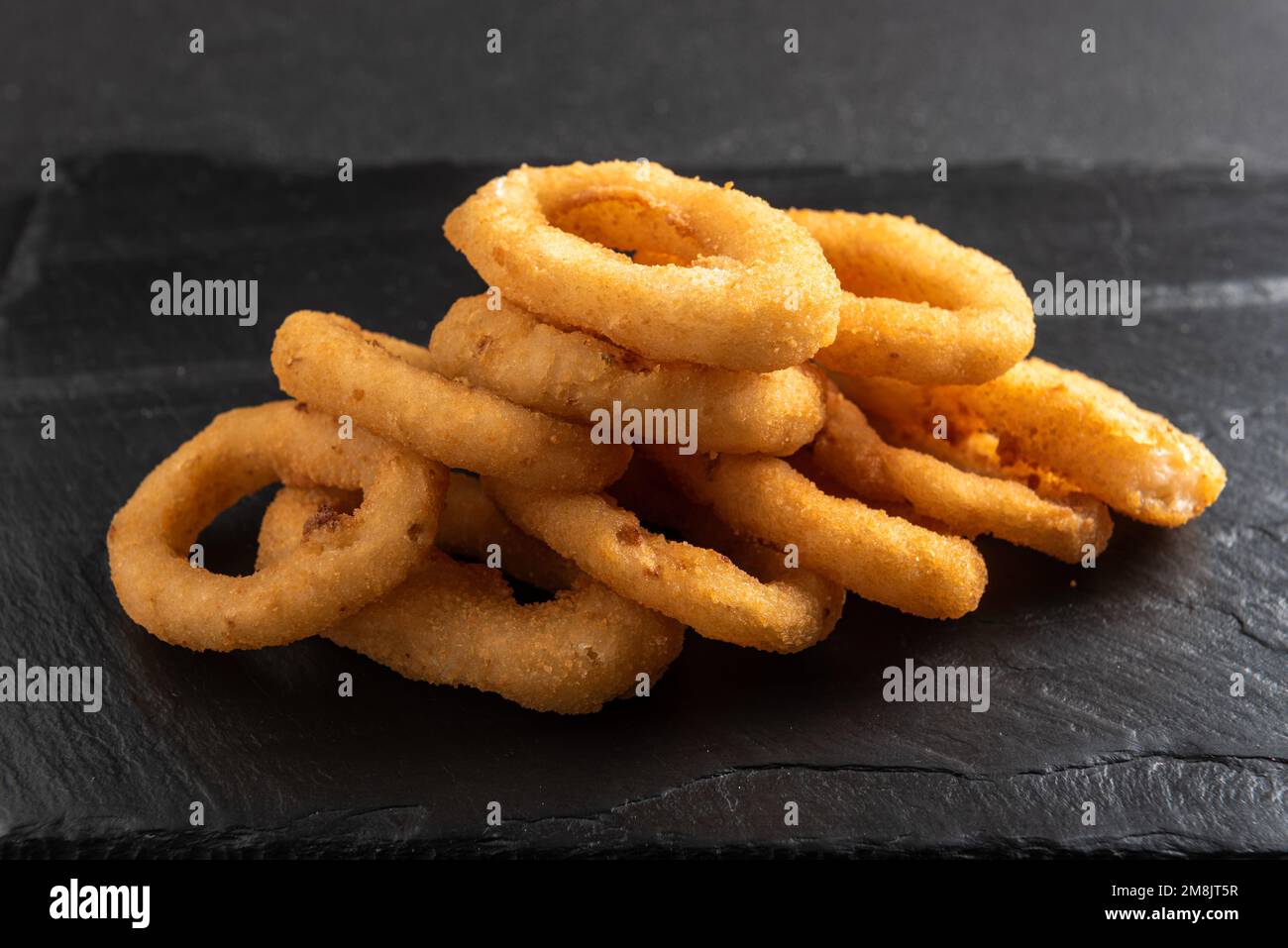 Calamari rings deep-fried in breading. Crispy squid rings on a dark ...