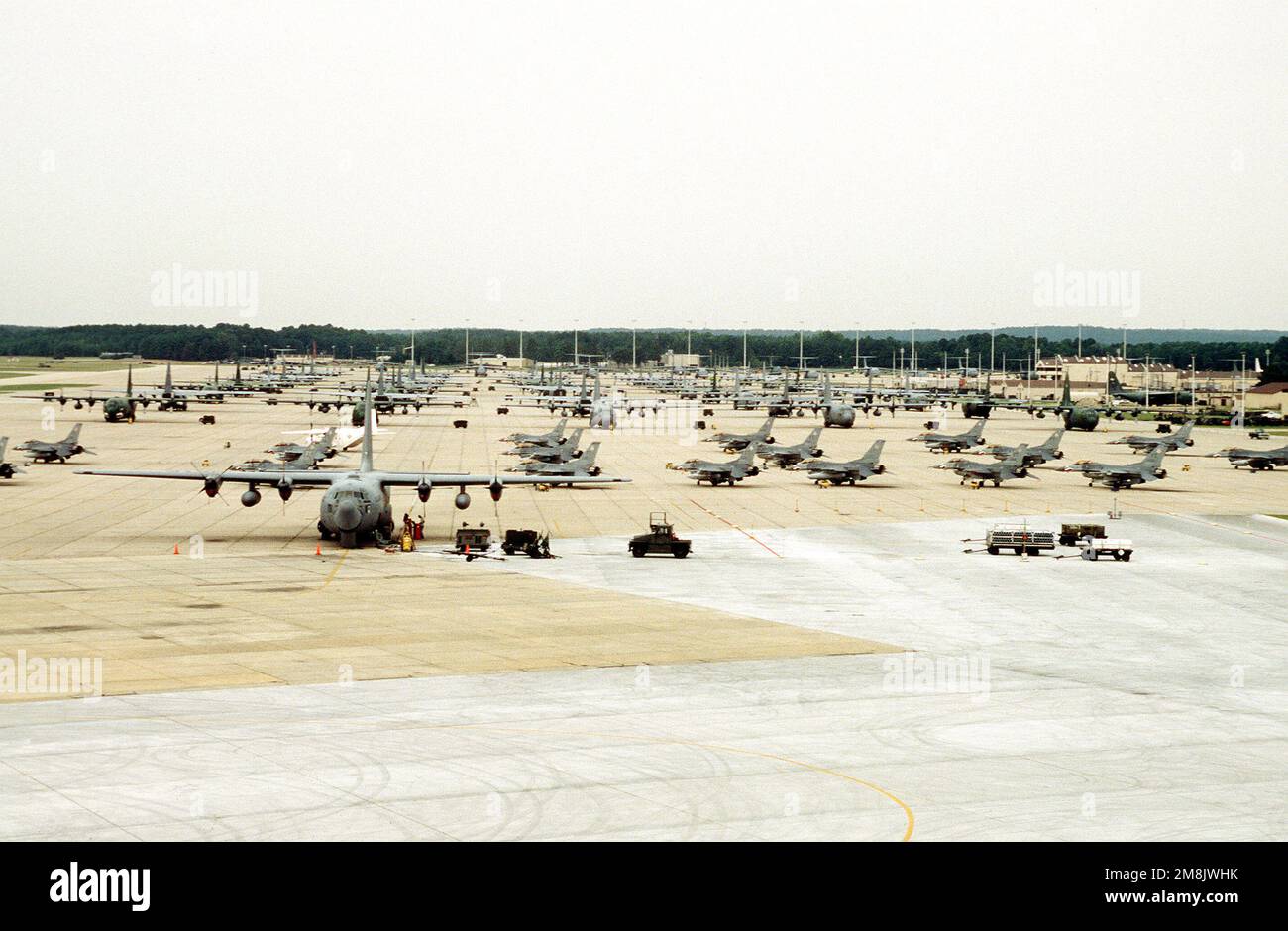 C-130, F-16, and C-141 aircraft line the flightline while waiting to ...