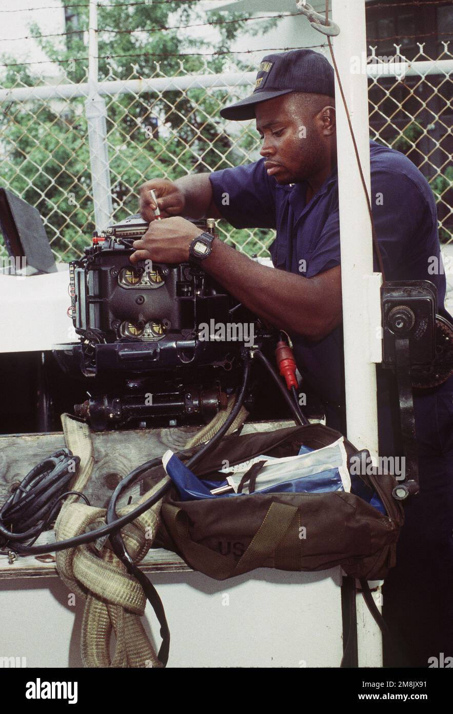 U.S. Coast Guard, MK3 Walter Prim, gives a tune-up to an Evinrude motor ...