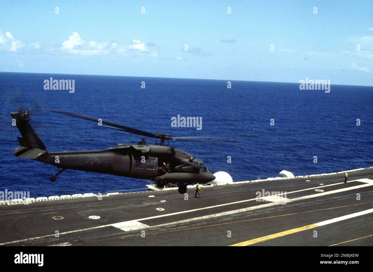 A UH-60 Black Hawk (Blackhawk) helicopter is guided in for a landing on ...