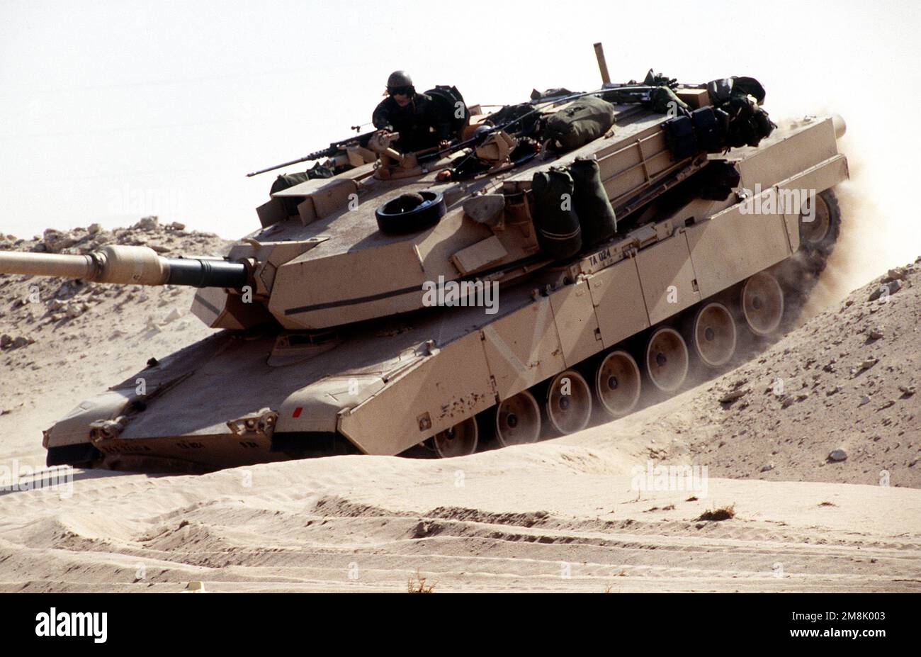 A M1A1 Abrams tank breaches a berm in the desert during maneuvers ...