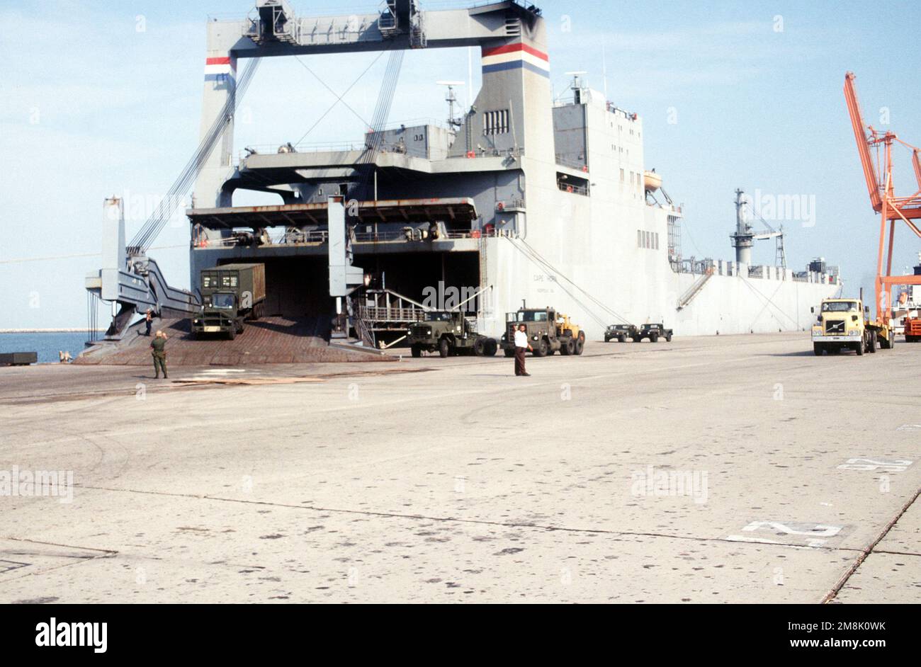 A US Army stevedore directs a tractor trailer down the ramp of the ...
