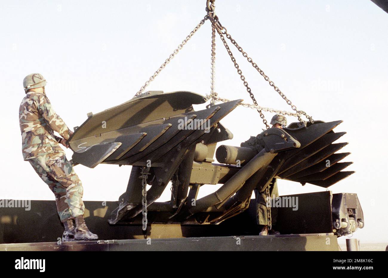 US soldiers load a mine plow for the M1A1 Abrams tank onto a cargo ...