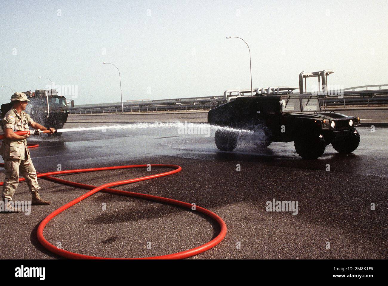A soldier from the 24th Infantry Division uses a fire hose to wash down ...