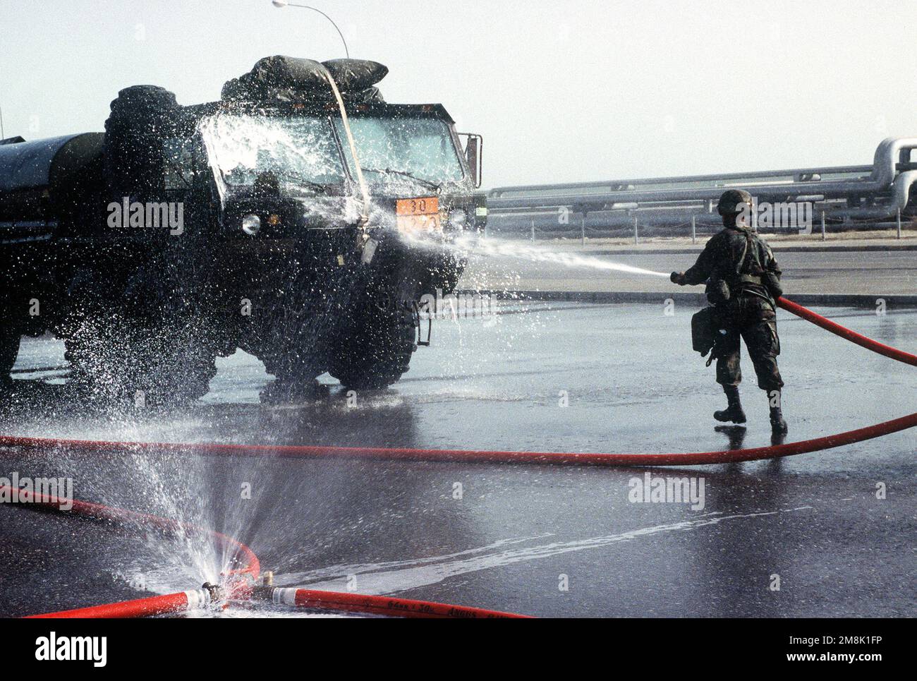 A soldier from the 24th Infantry Division uses a fire hose to wash down ...