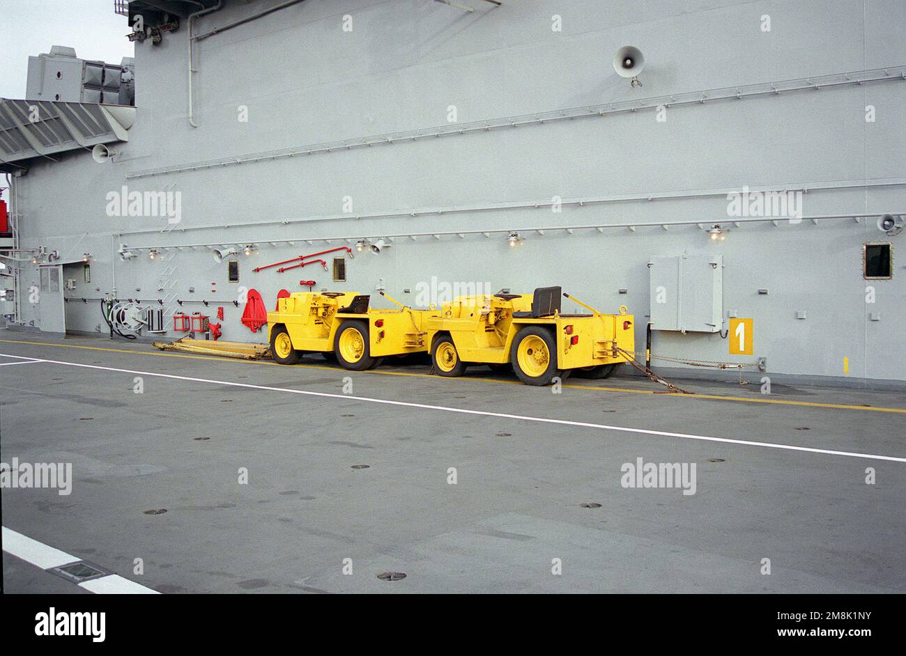 A view of two tow tractors secured to the flight deck alongside the ...