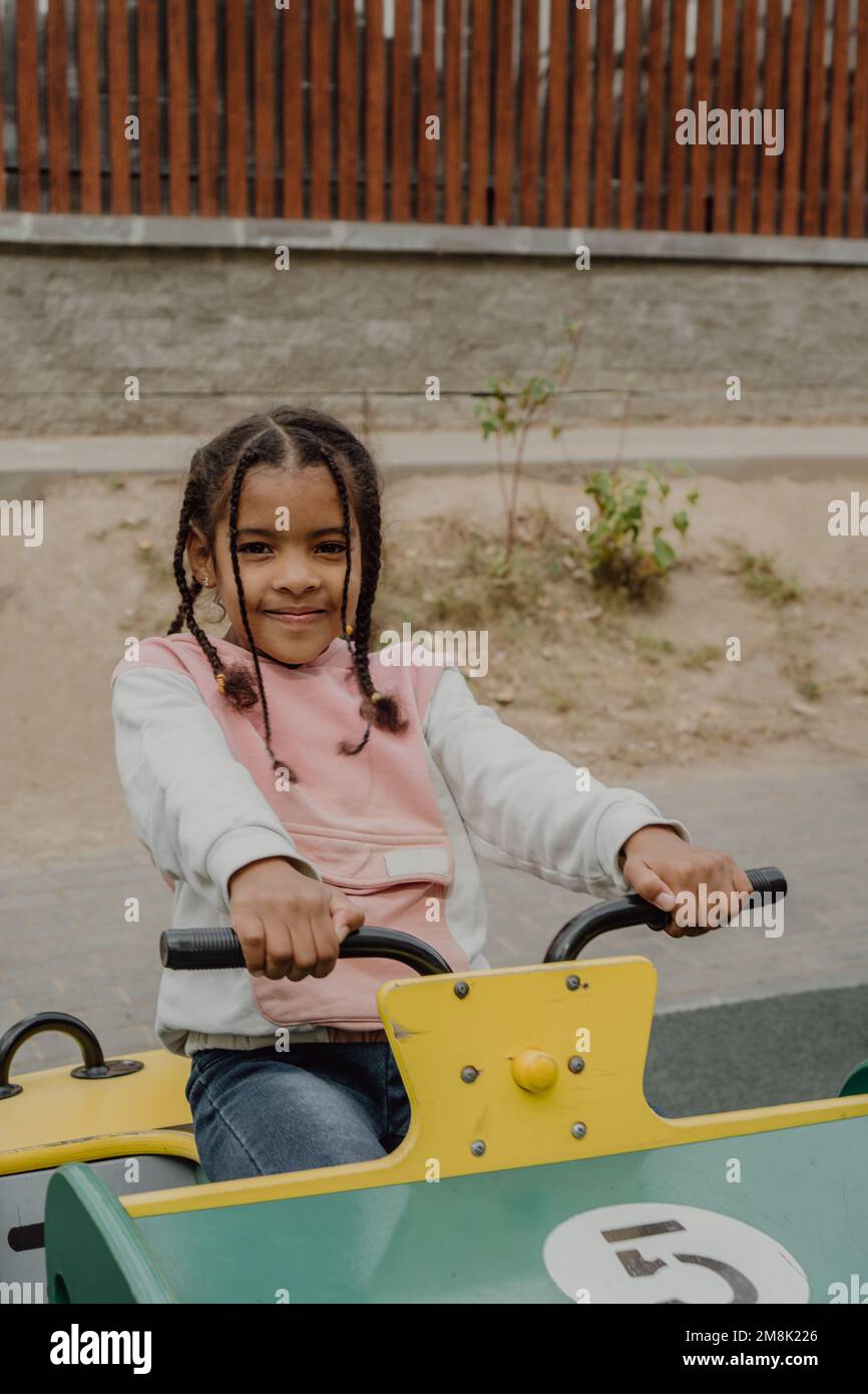A vertical shot of a happy little girl on a ride in a playground Stock ...