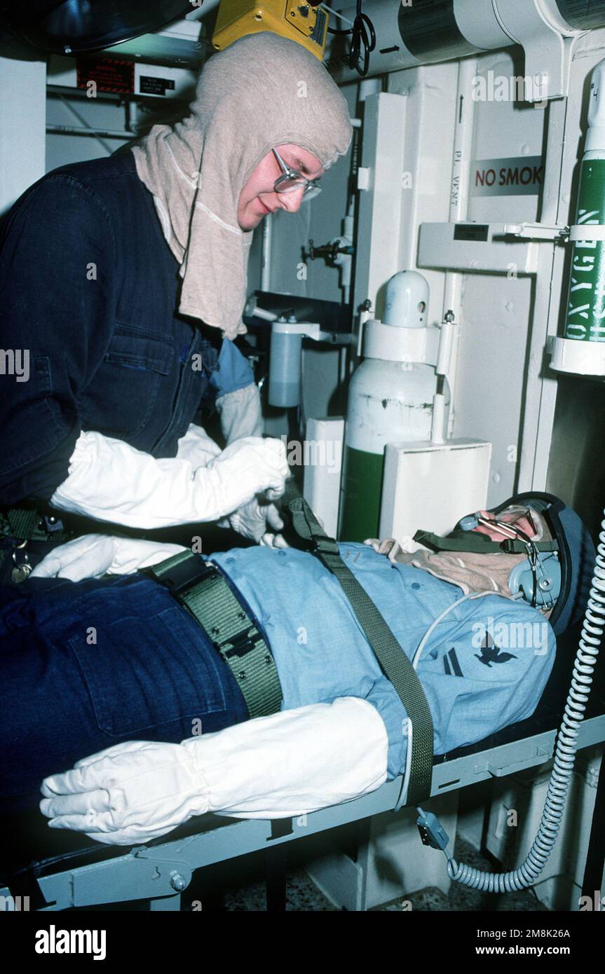 A damage control petty officer straps a "wounded" sailor down in sick ...