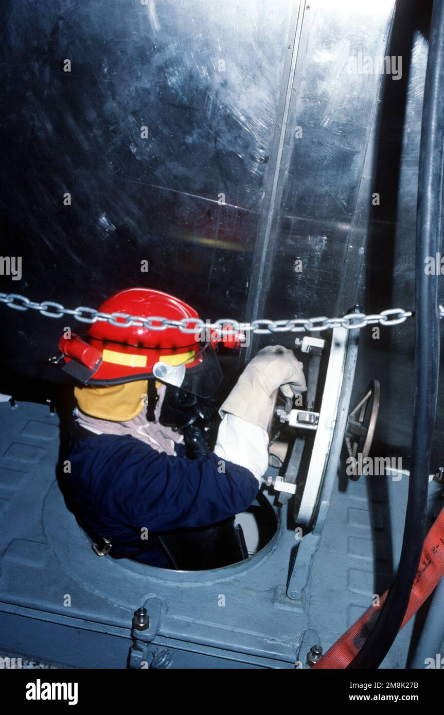 A damage control sailor is shown passing through the escape shuttle in ...