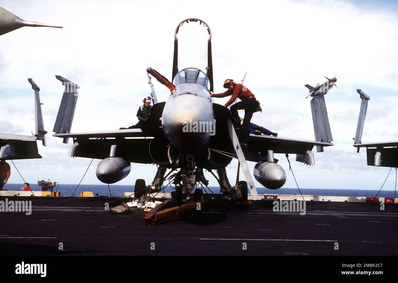 A US Navy F/A-18 Hornet is readied for a mission by a crew on the ...