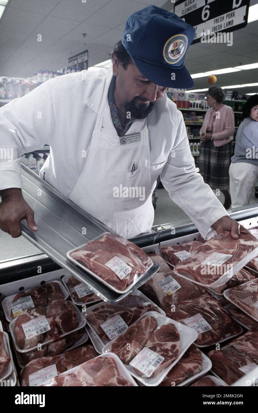 A butcher places wrapped cuts of meat into the refrigerated meat ...