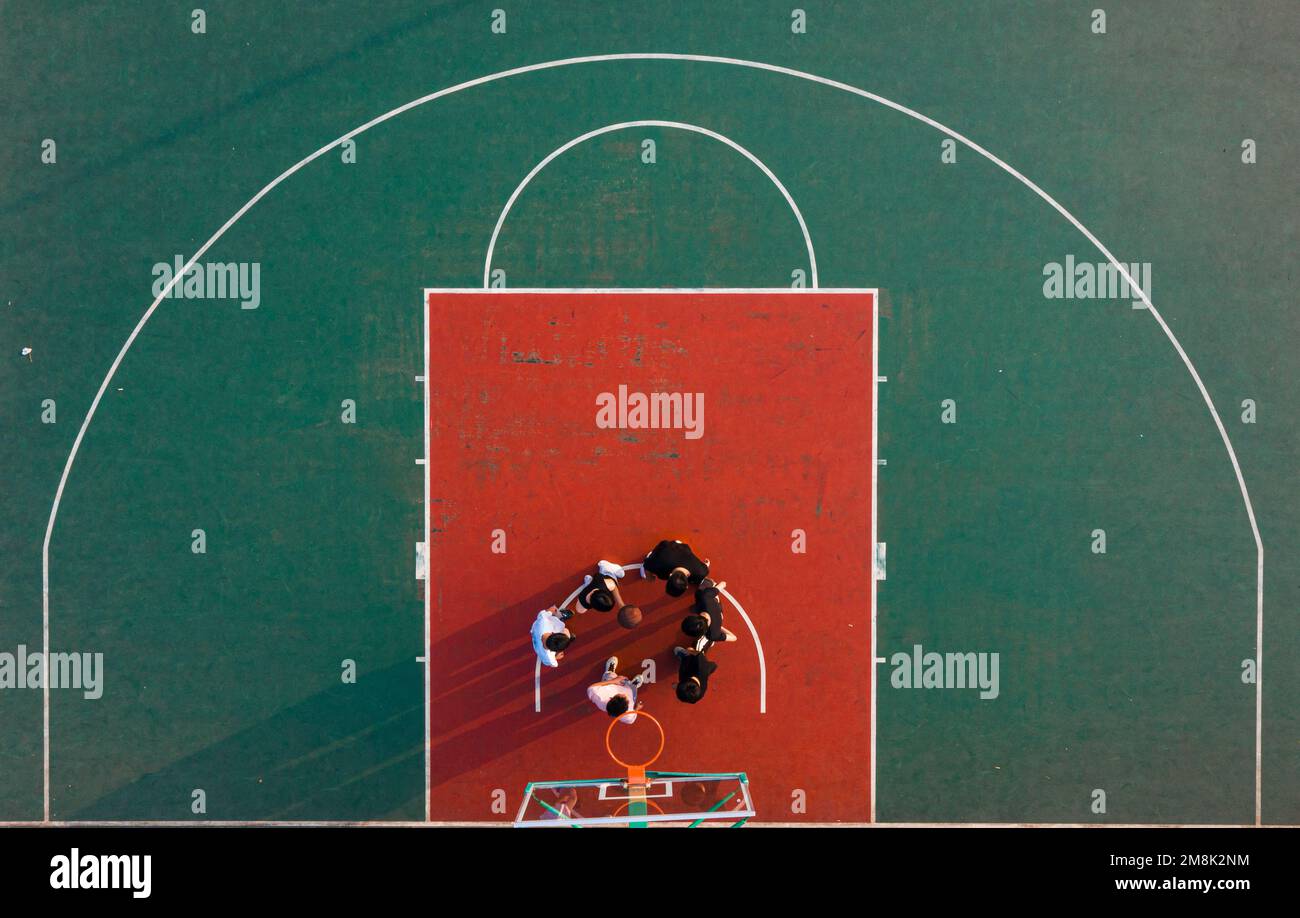 An aerial top view of a basketball court and young people gathered ...
