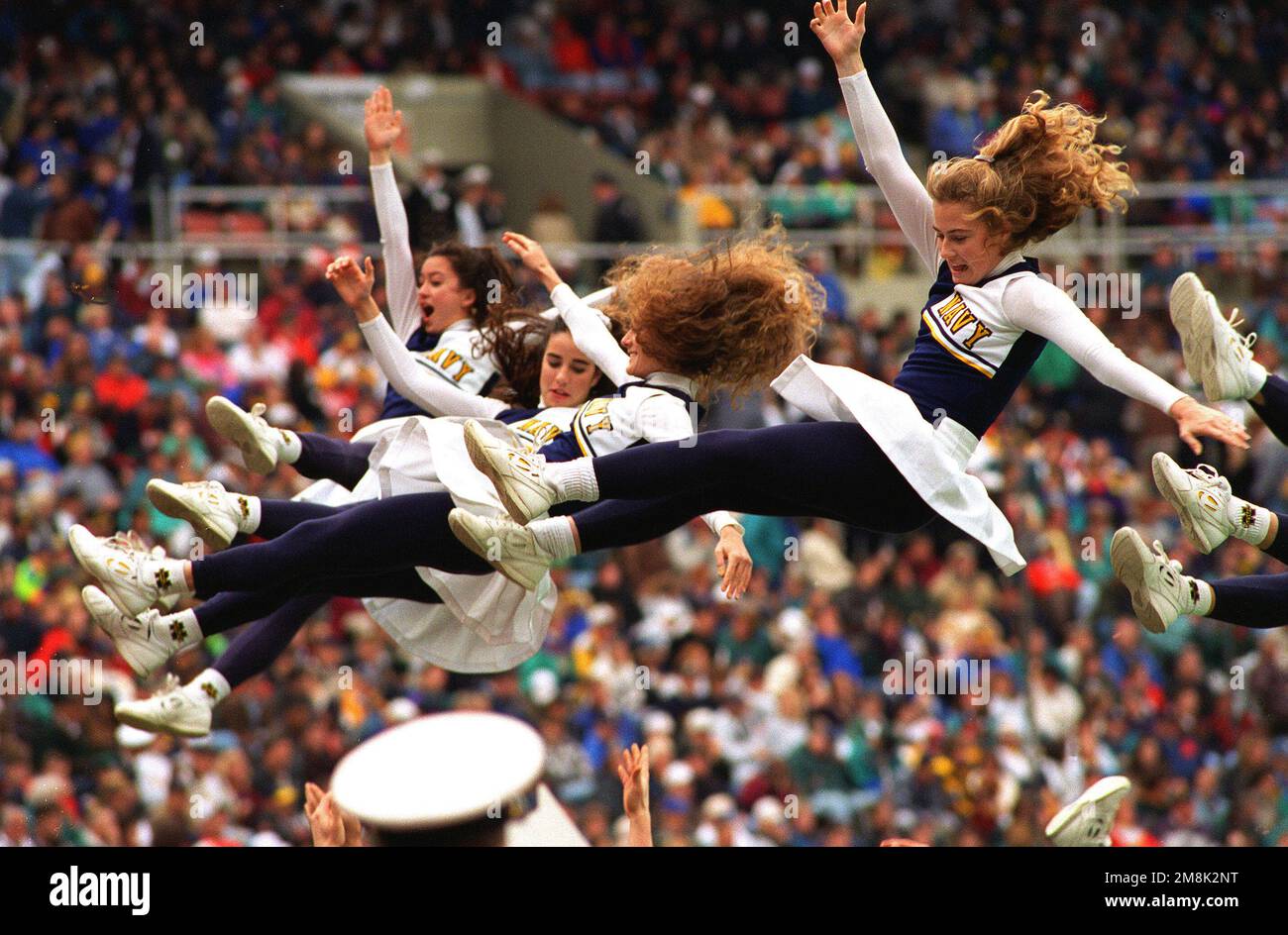 U.S. Naval Academy cheerleaders are tossed high in the air during the ...