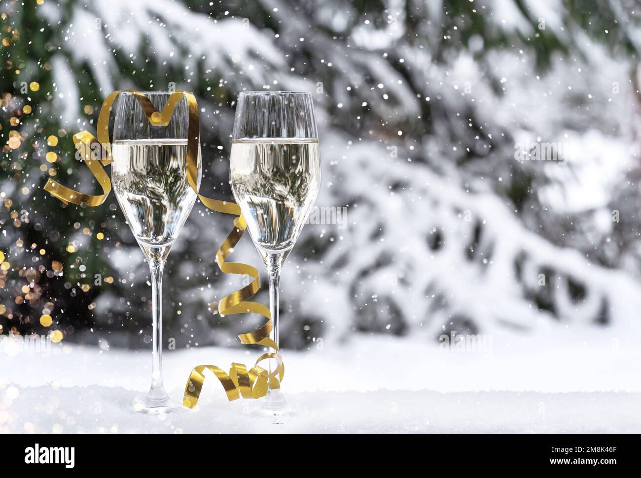Closeup of two champagne flutes cooling in snow decorated with party ...