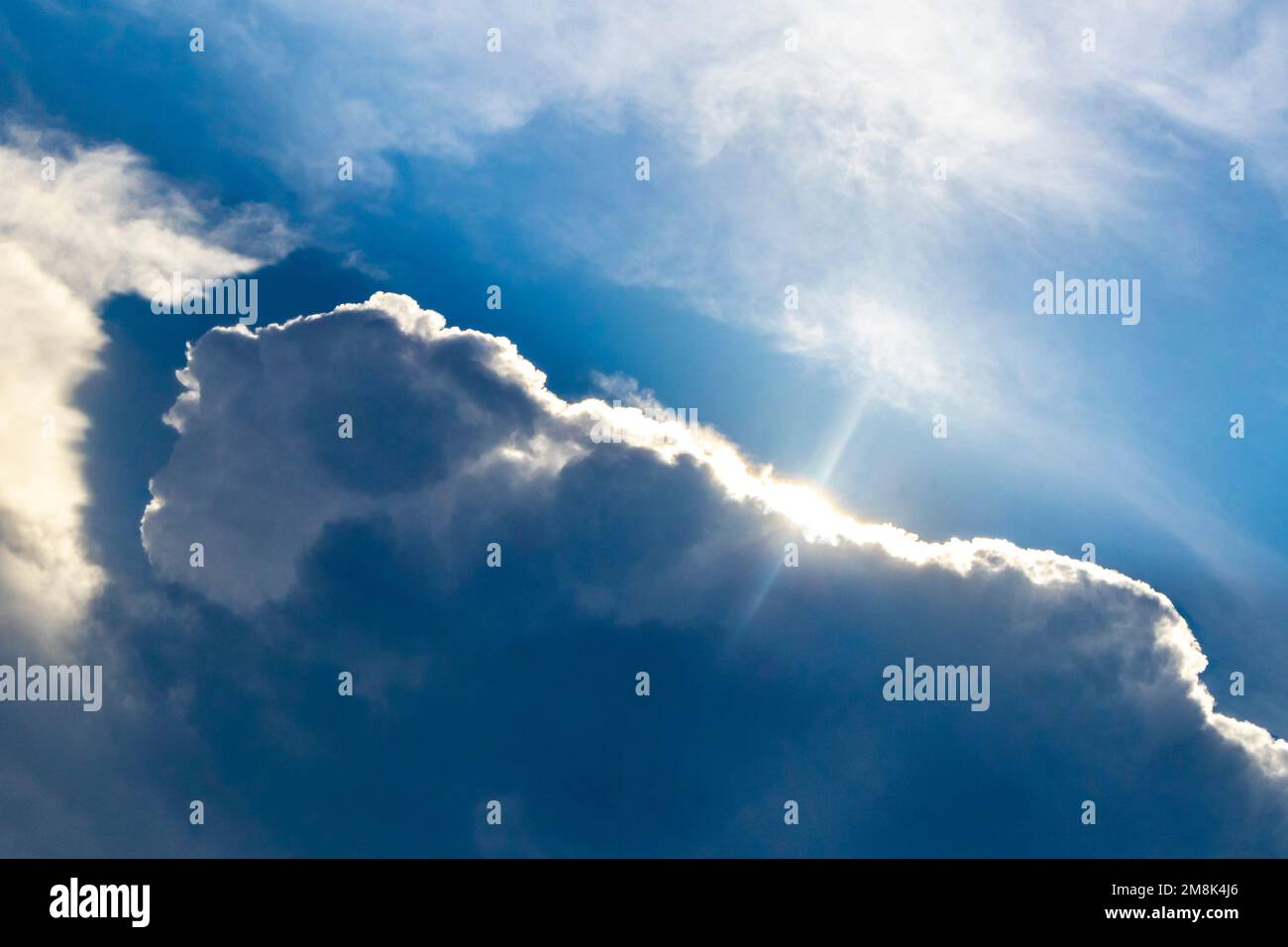 The sun comes out from behind the clouds with blue sky background in ...