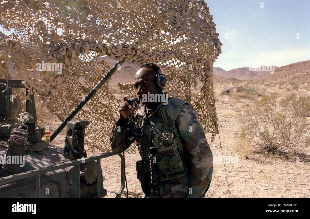 Gun crewmen, wearing headset in front of an M998 High-Mobility ...