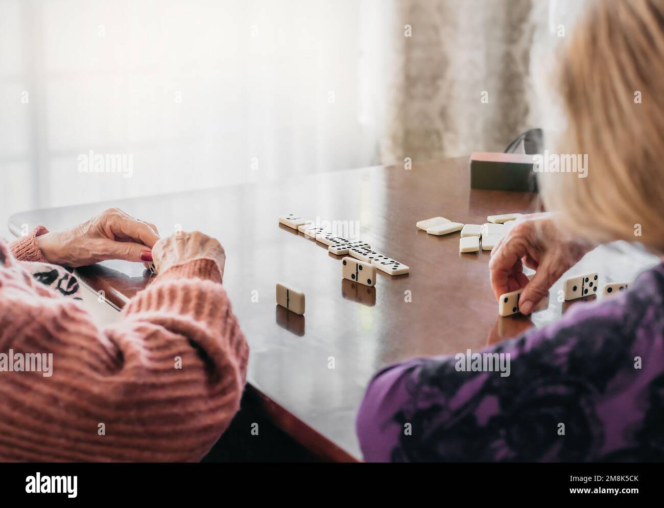 rear view of two elderly people playing dominoes. concept of fun and ...