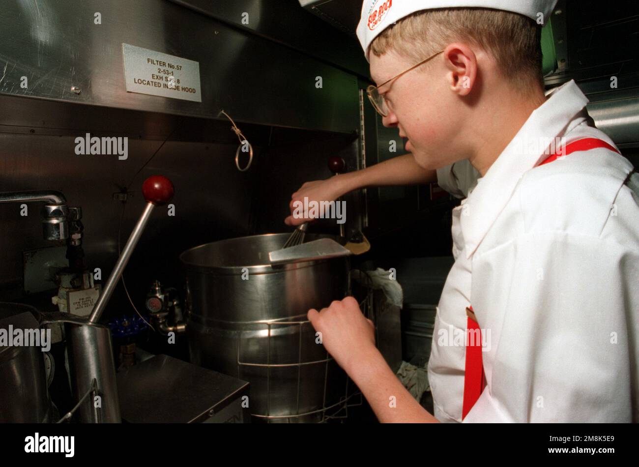 A mess specialist cook prepares soup for the crews afternoon meals on ...