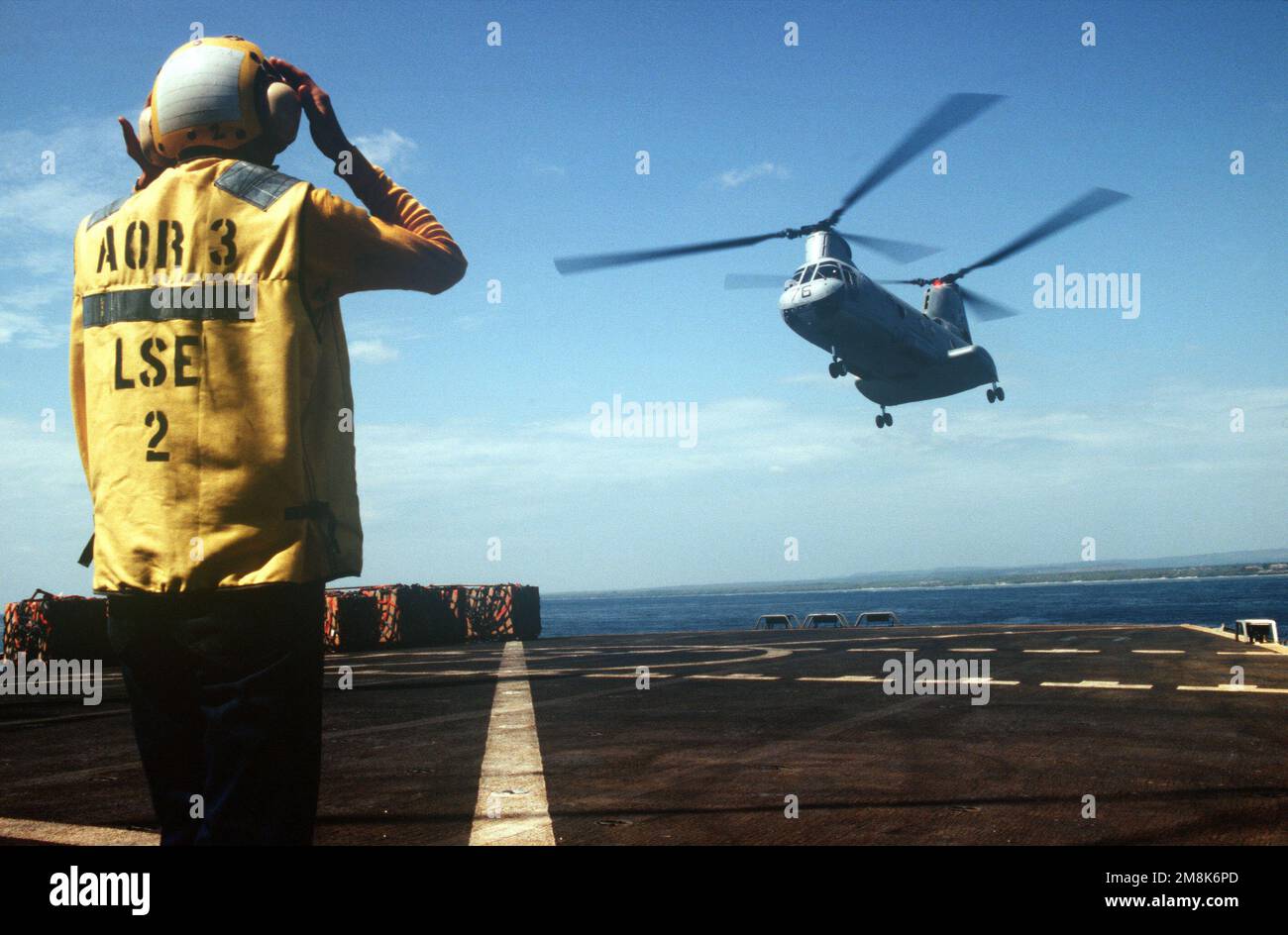 Operation UNITED SHIELD. A flight deck crewman directs a US Navy CH-46 ...