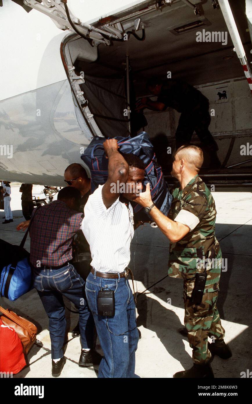 Haitian migrants, with the help of Joint Task Force 160 personnel, load ...