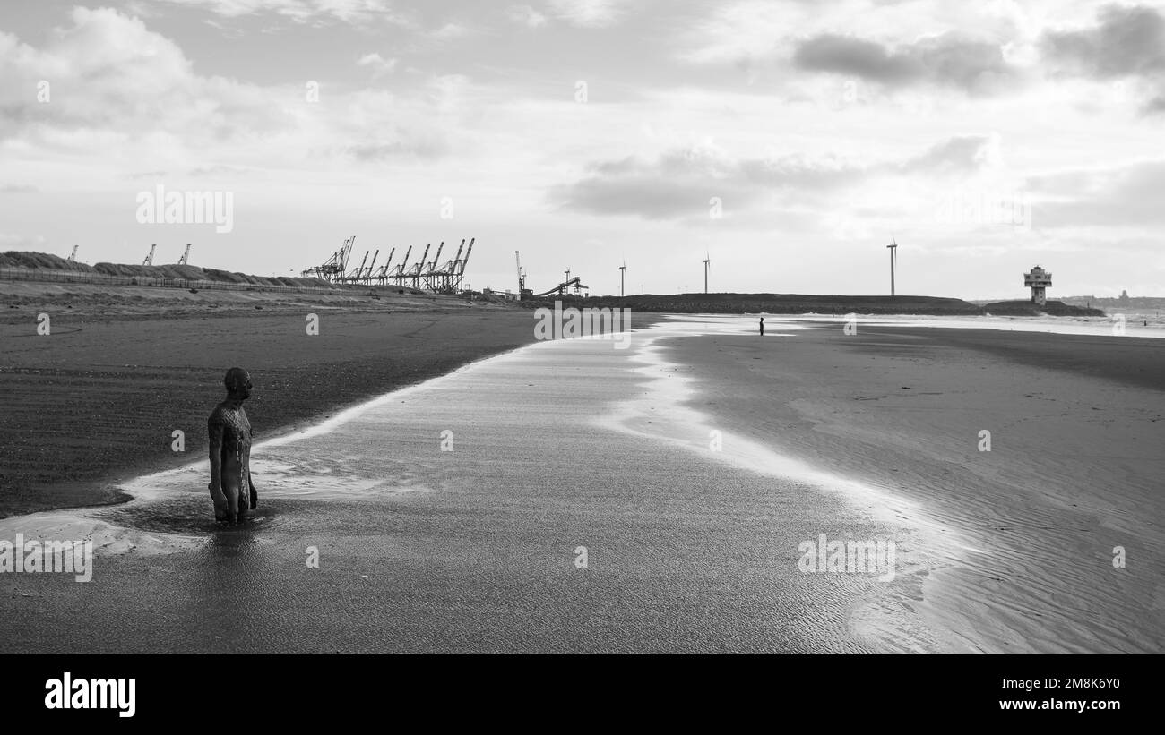 An Iron Man seen in a long channel of water on the beach at Crosby near ...