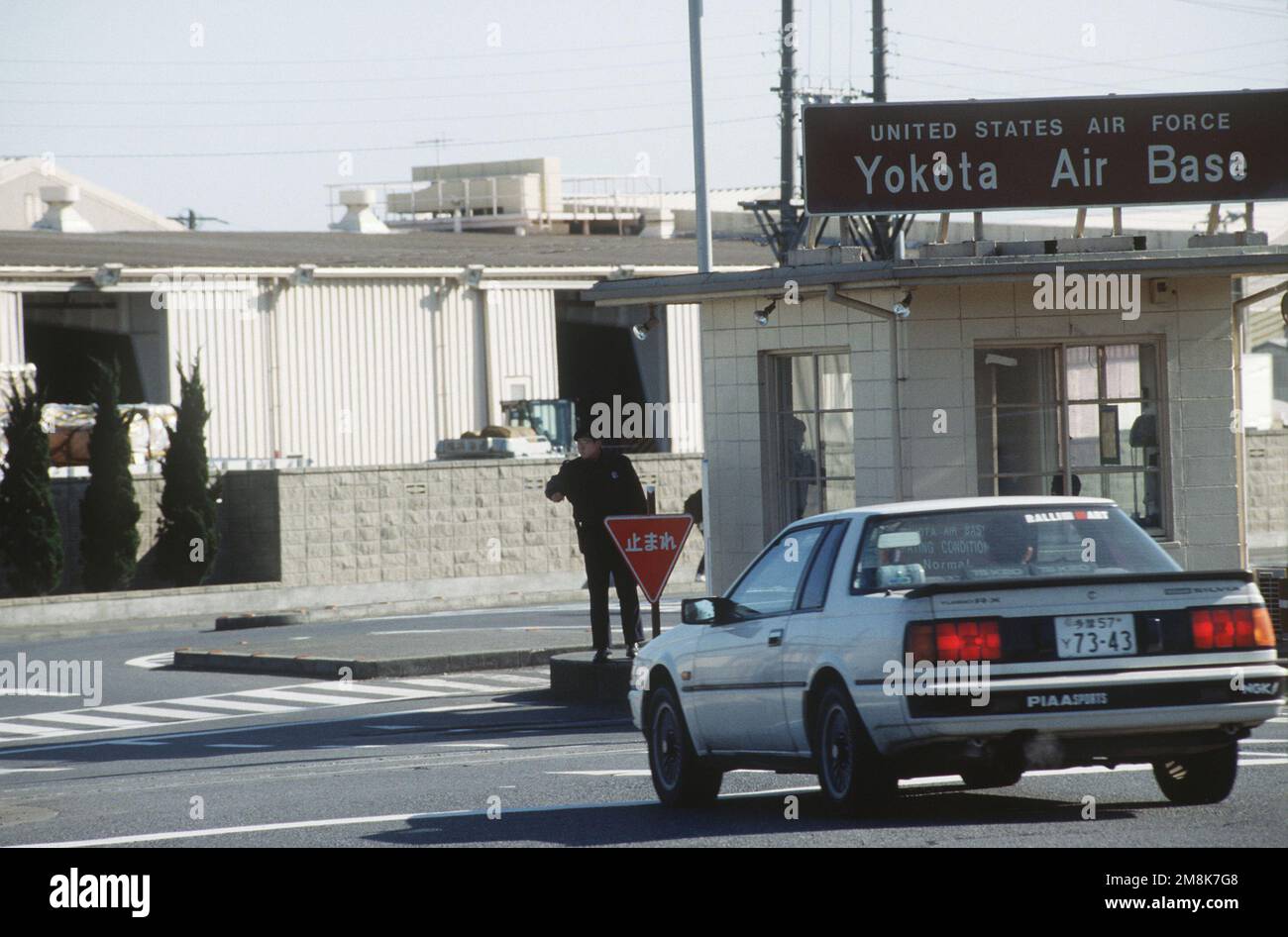 A security policeman waves in a vehicle at the main gate. Base: Yokota ...