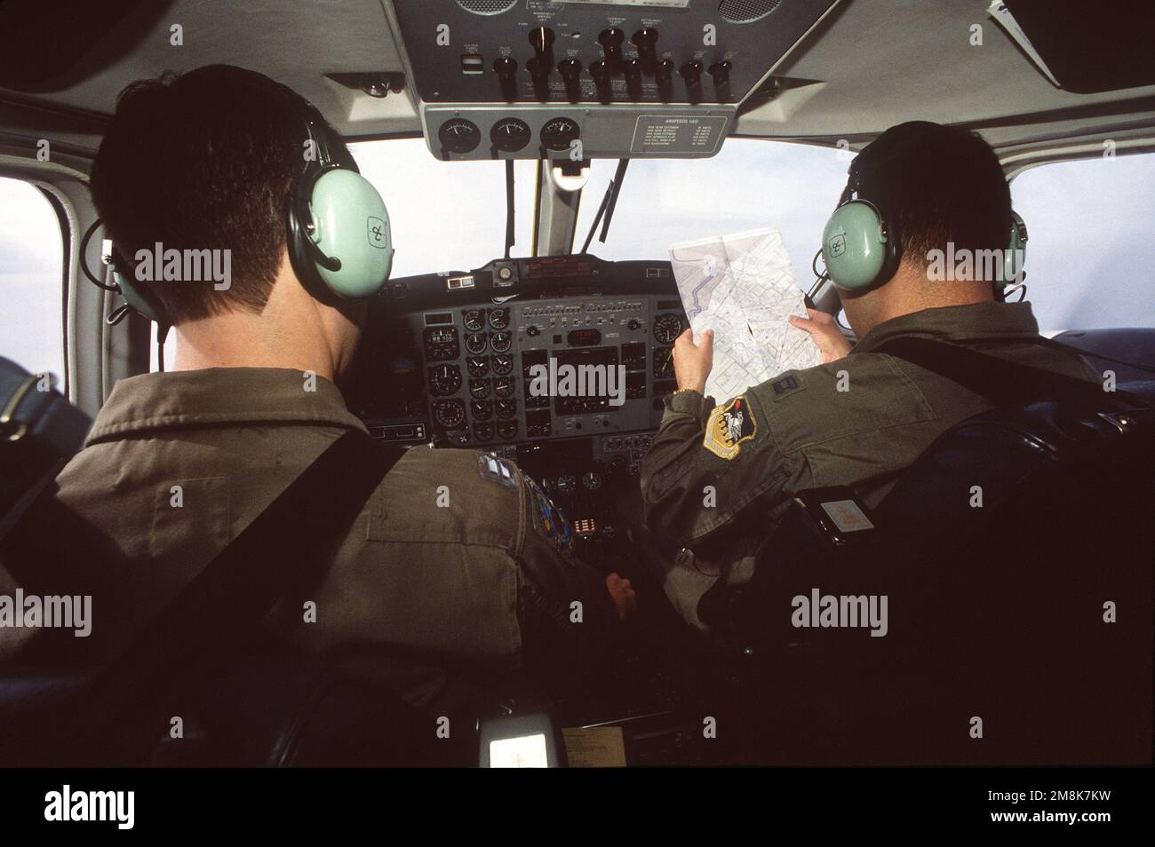 The co-pilot studies a map in the cockpit of a C-12J as the pilot looks ...