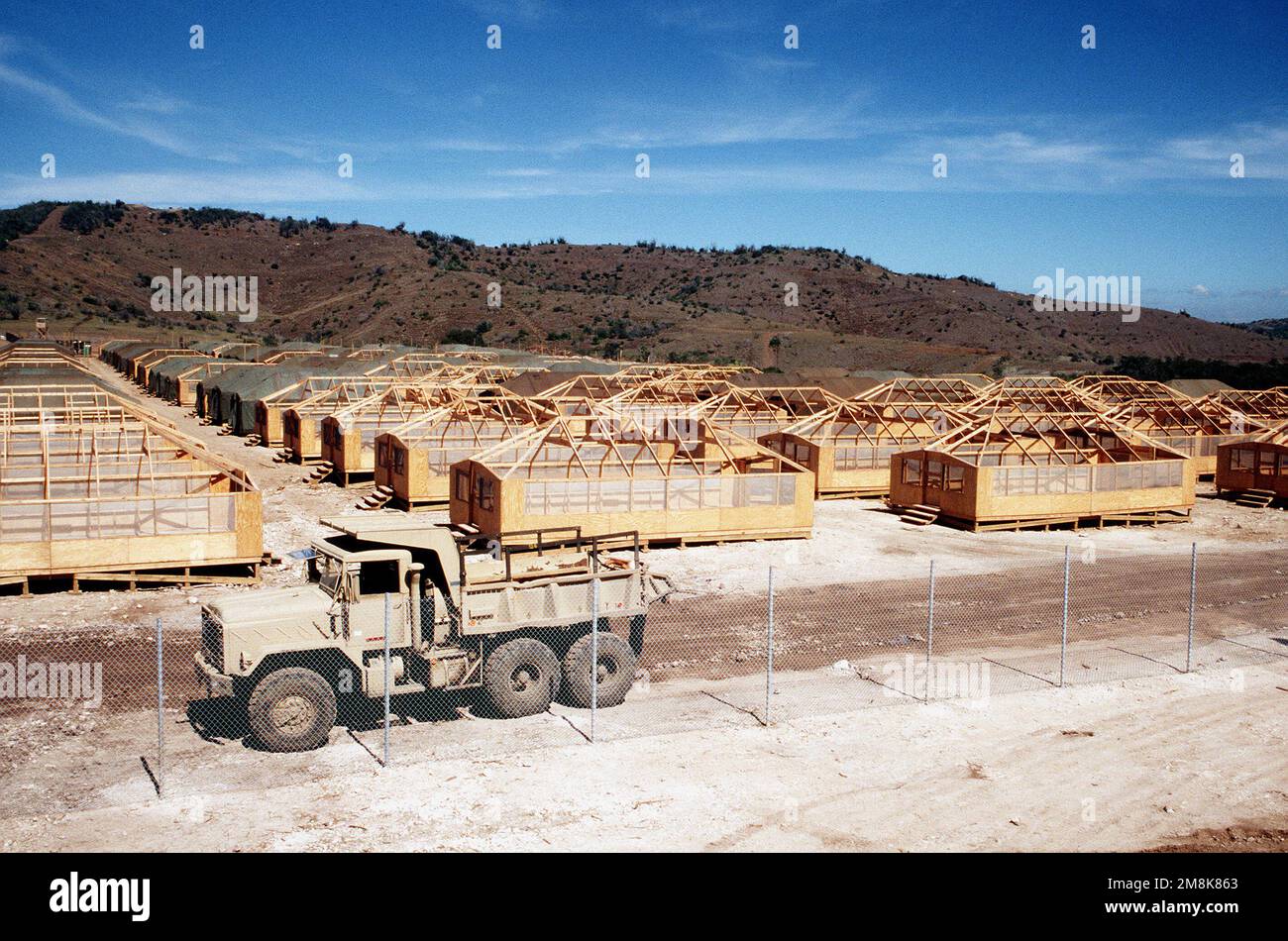 Hard back tent frames are lined up in rows. U.S. Navy Seabees from ...