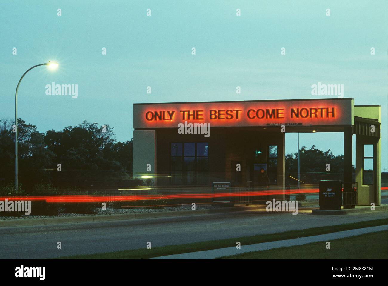 A close-up night view of the main gate with the sign illuminated. Base ...