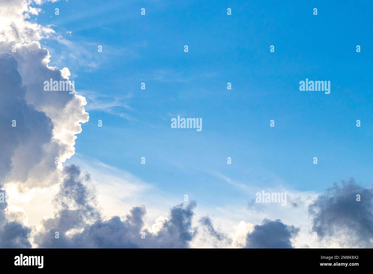 The sun comes out from behind the clouds with blue sky background in ...