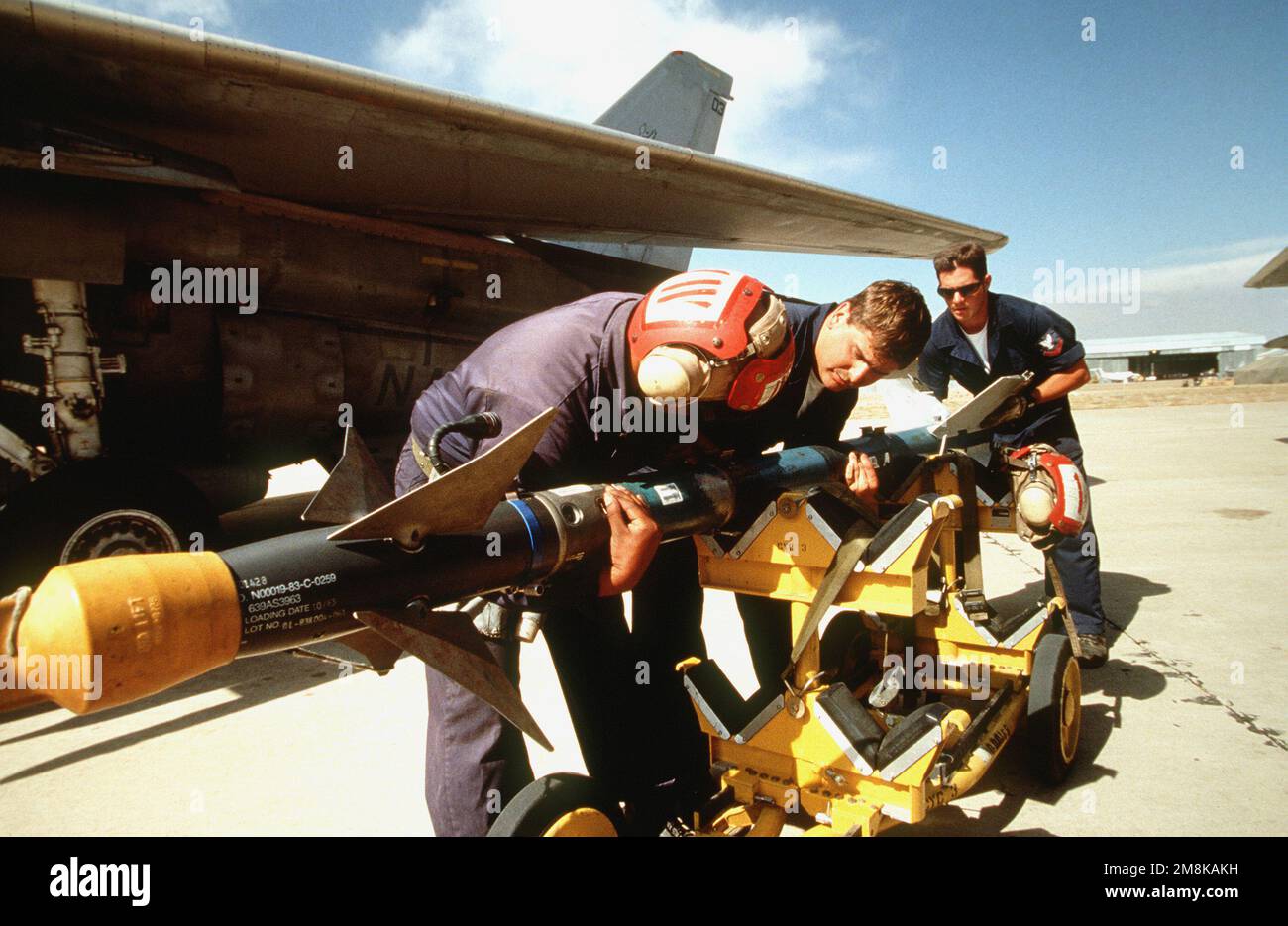 US Navy aviation ordnancemen lift an AIM-9 Sidewinder missile from a ...
