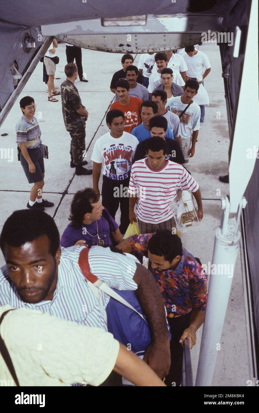 Cuban migrants board an aircraft on the flight line at US Naval Base ...