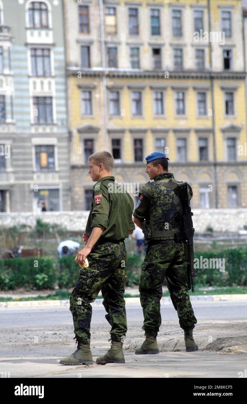 Two United Nations peacekeepers stand amidst the war-damaged buildings ...